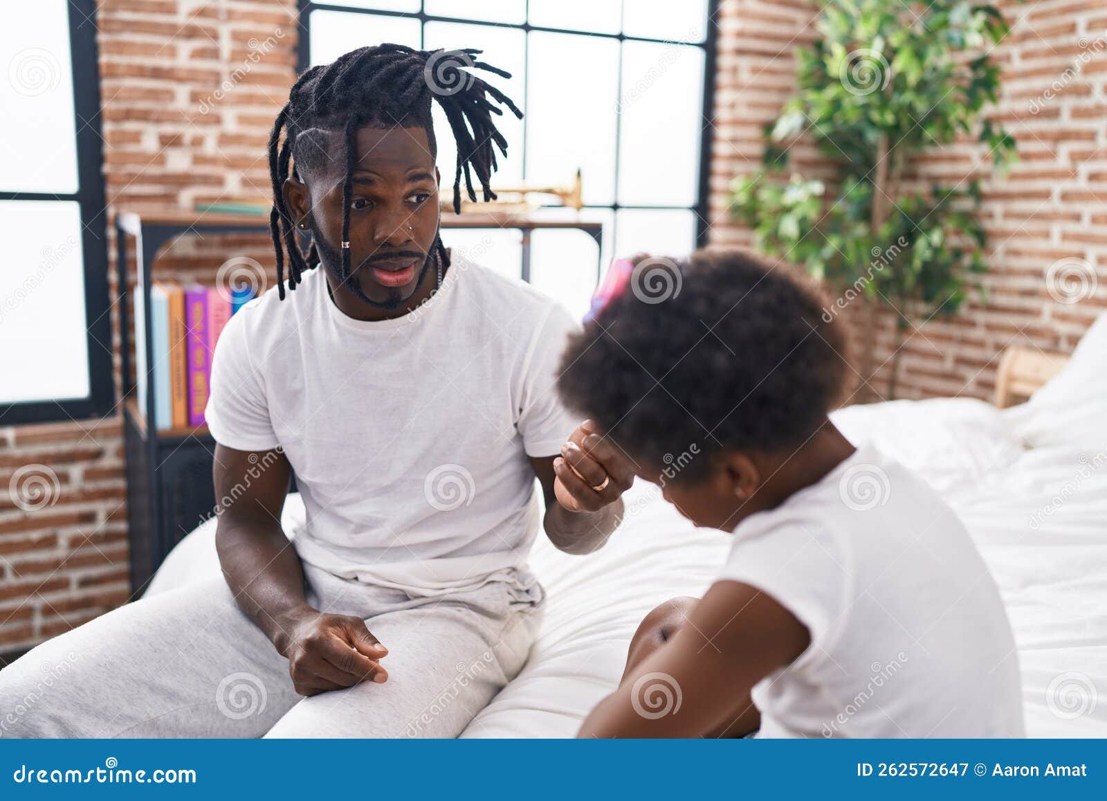 Father and Daughter Sitting on Bed Speaking with Serious Expression at ...