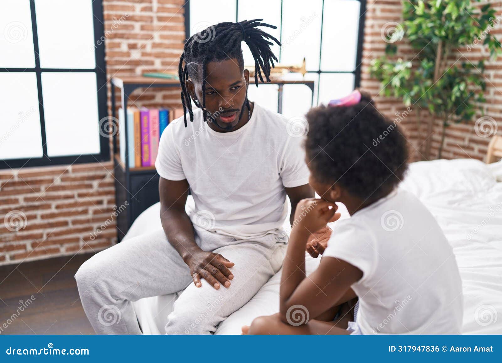 Father and Daughter Sitting on Bed Speaking with Serious Expression at ...