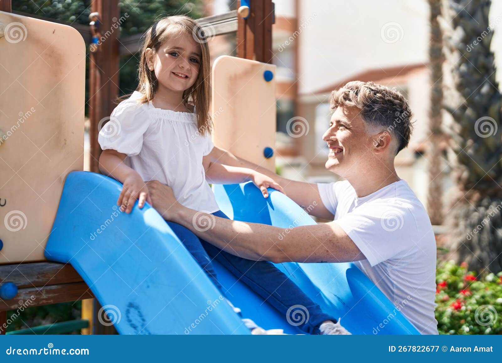 Father and Daughter Smiling Confident Playing on Slide at Playground ...