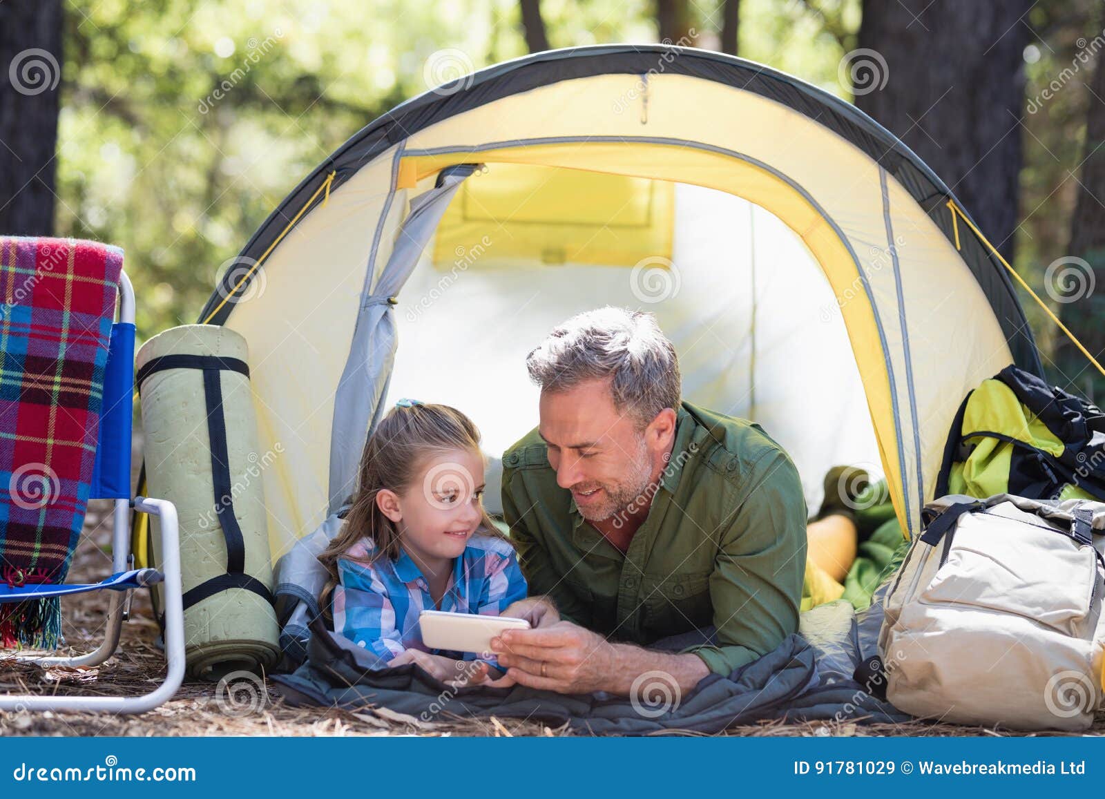 Father and Daughter Using Mobile Phone while Relaxing in Tent Stock ...