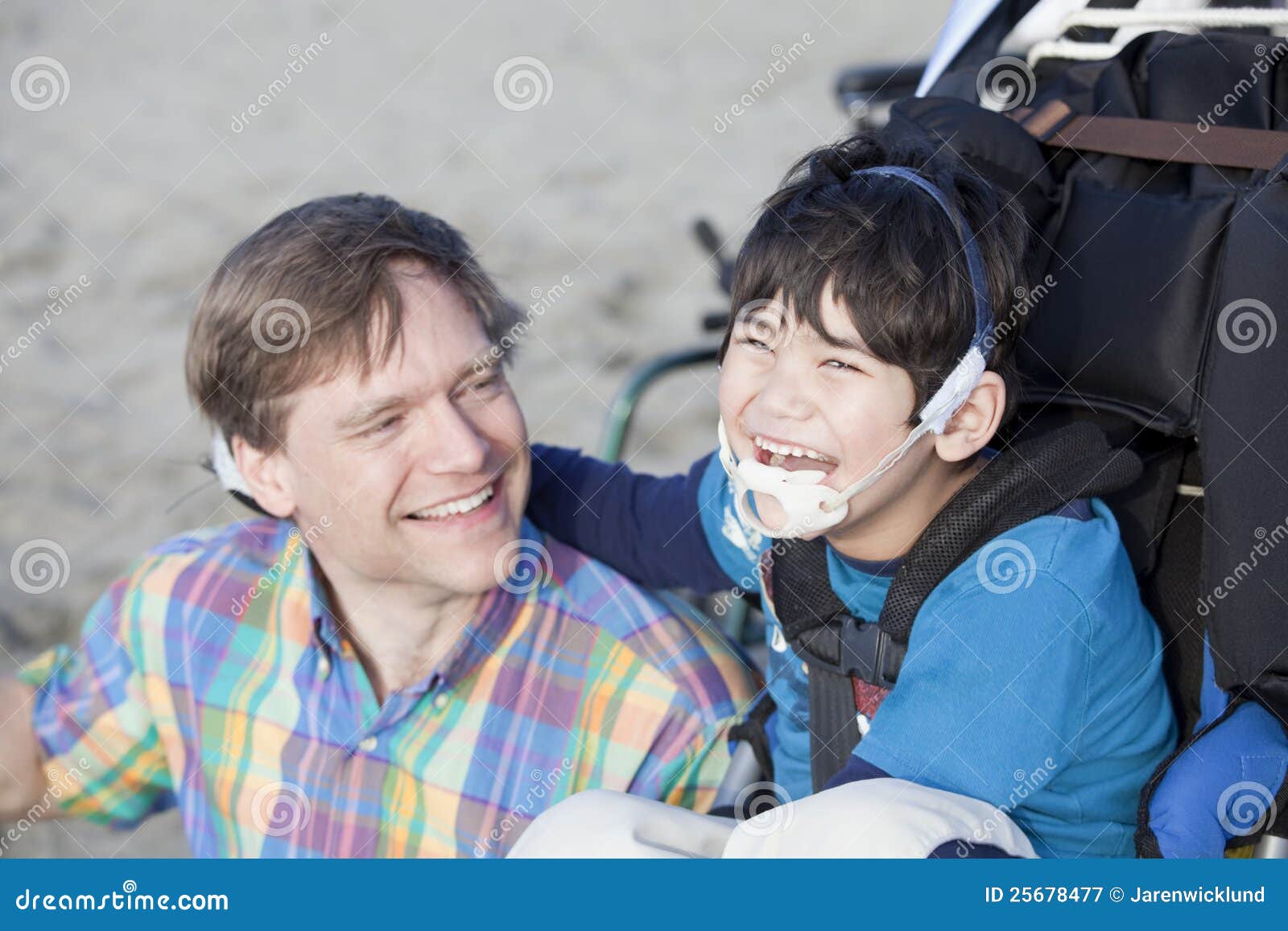 Father With Disabled Son In Wheelchair On Cold Foggy Beach Royalty-Free ...
