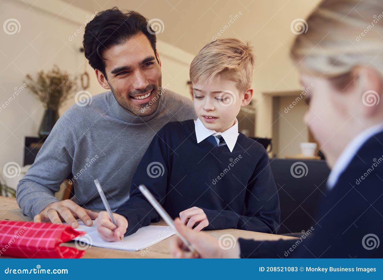 Father Helping Son and Daughter Wearing School Uniform with Homework at ...
