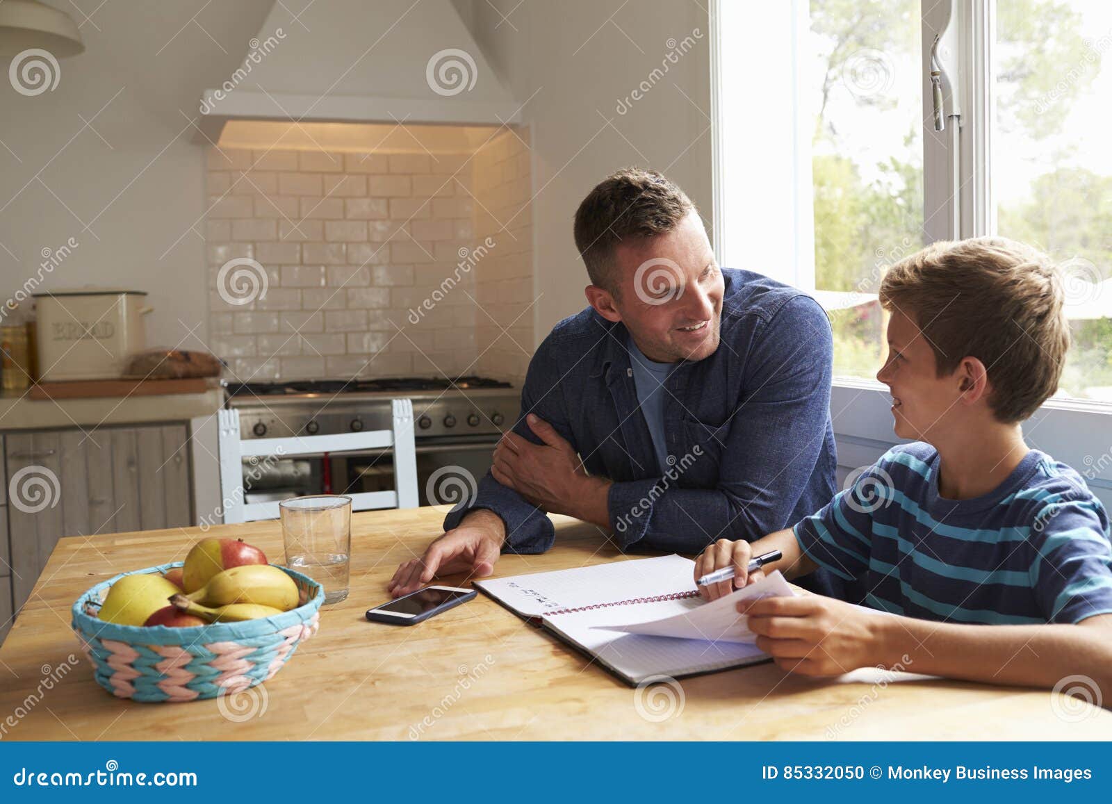 Father Helping Son with Homework Sitting at Kitchen Table Stock Photo ...