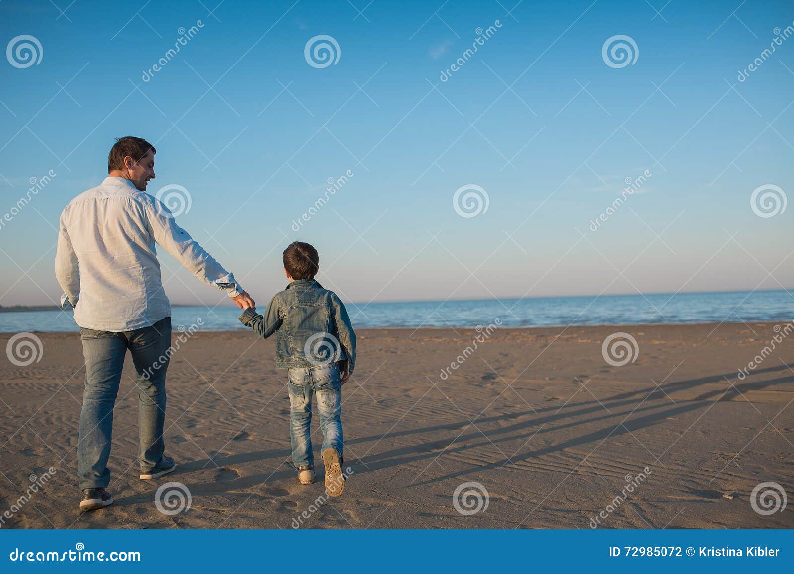 Father and His Little Son Walk on a Beach in the Evening. Back View ...