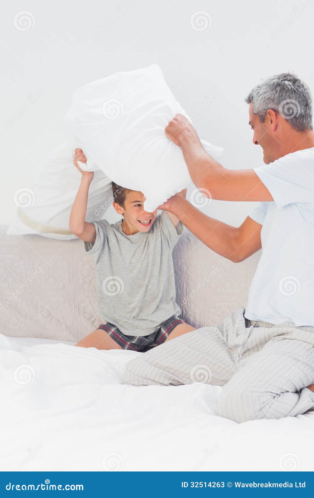 Father and Son Fighting Together with Pillows on Bed Stock Image ...