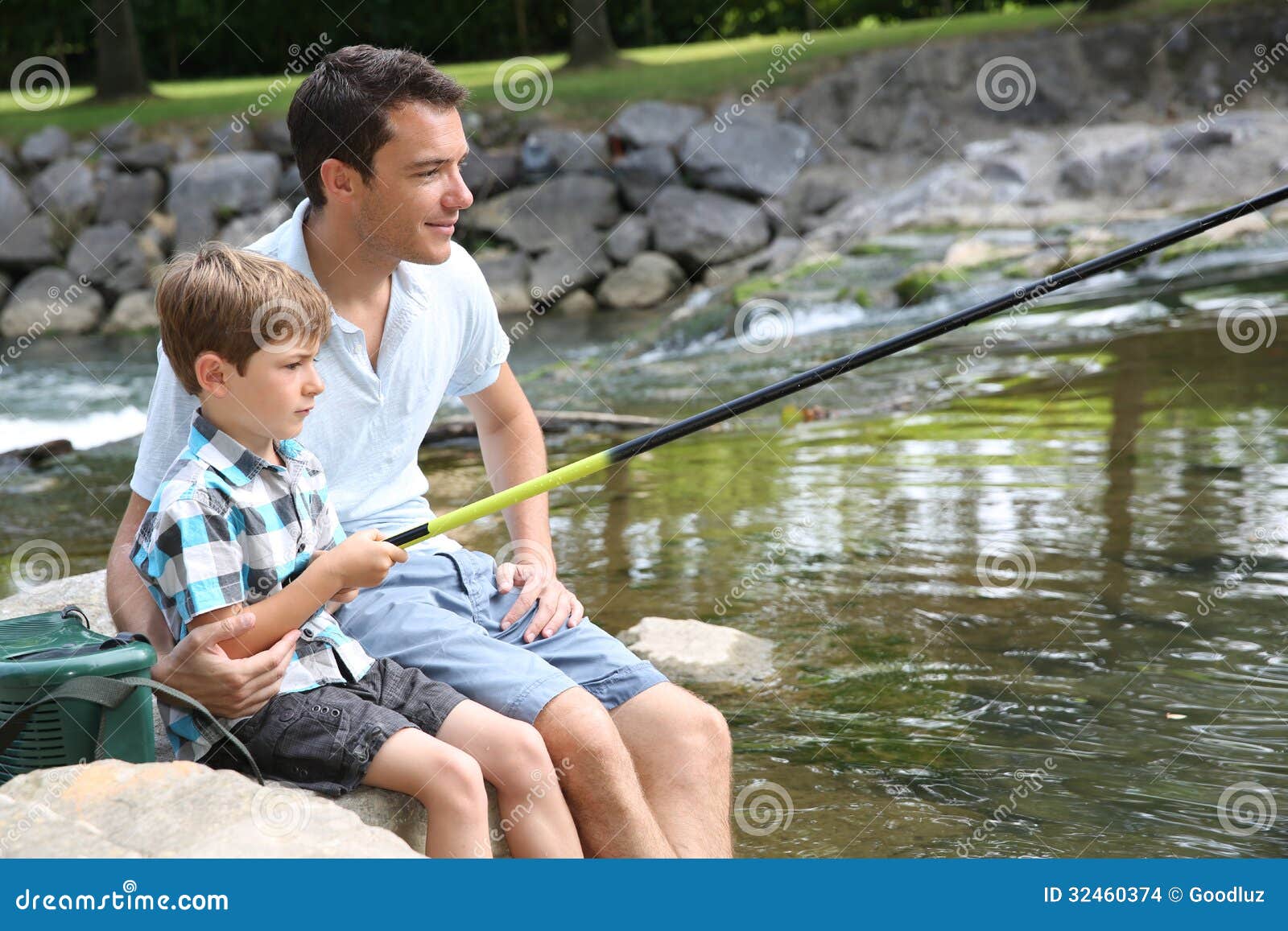Father With Son On The River Enjoying Fishing Holding Fishing Rods ...