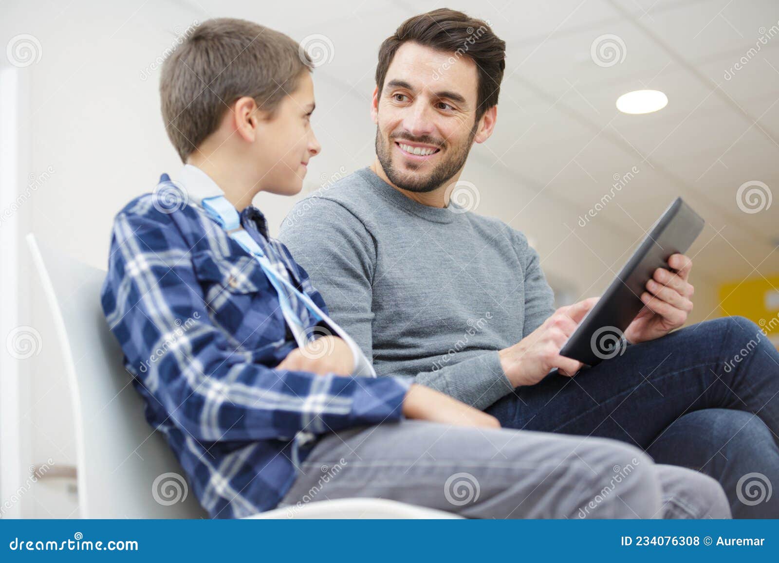 Father with Son in Hospital Waiting Room Looking at Tablet Stock Photo ...