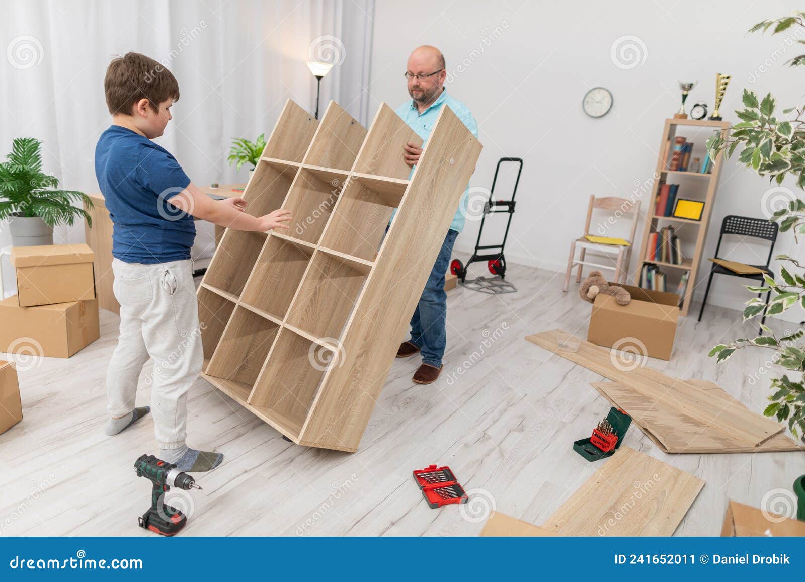 A Father and Son Lift a Folding Bookcase Upright. Stock Image - Image ...
