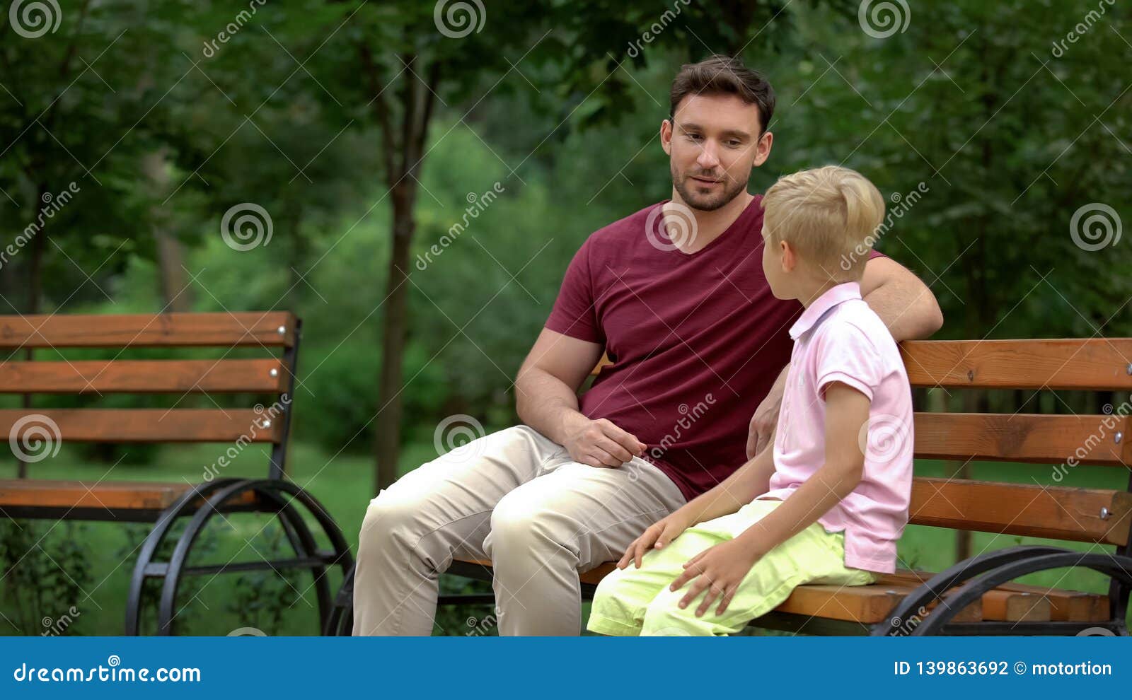 Father And Son Sitting On Bench In Park Men Talks Spending Time