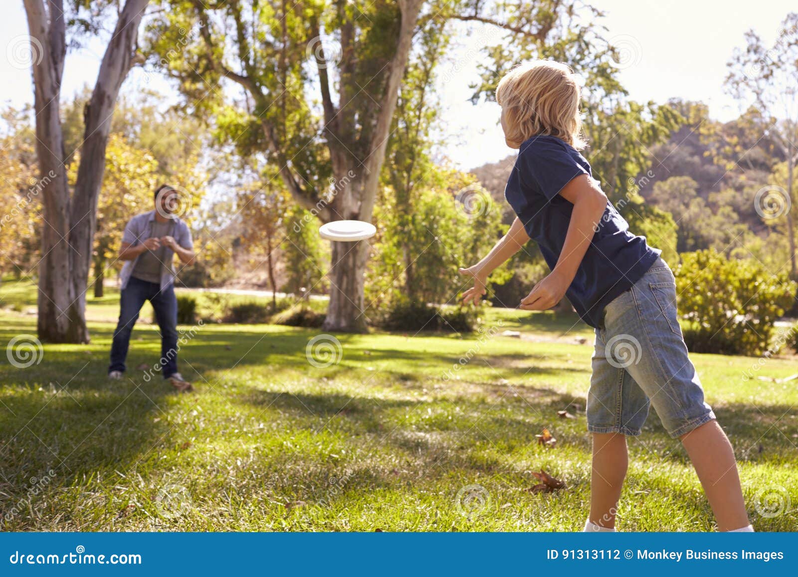 Father and Son Throwing Frisbee in Park Together Stock Photo - Image of ...