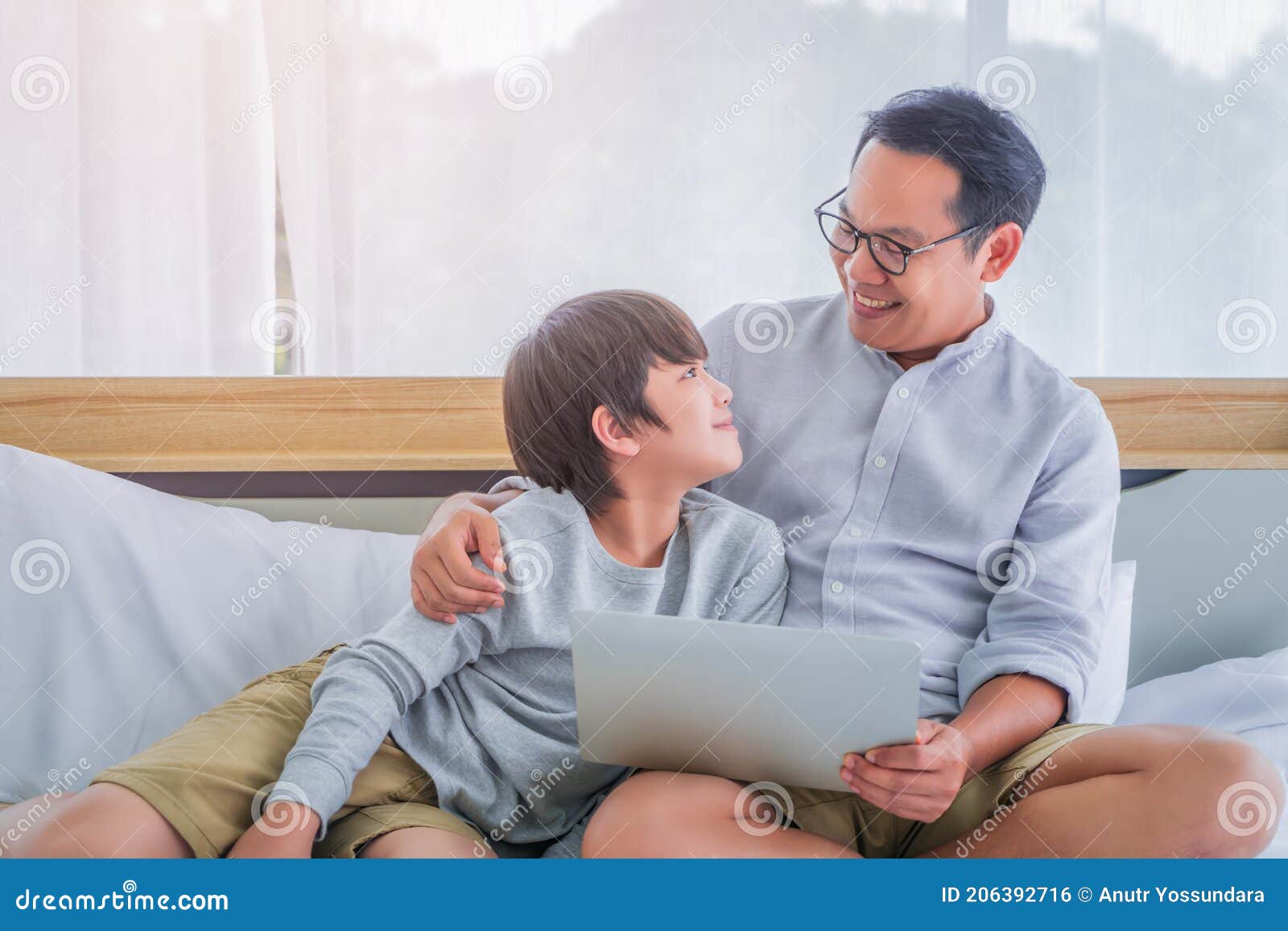 Father and Son Using Laptop Computer on the Bed Together for Technology ...
