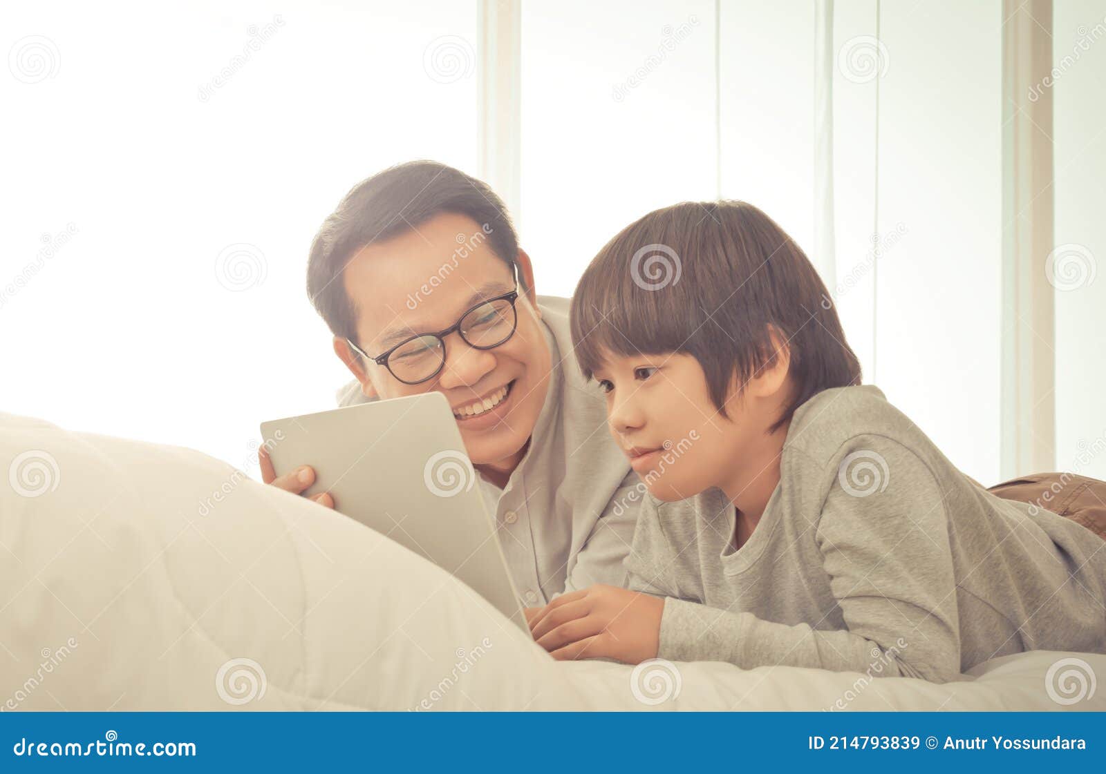 Father and Son Using Laptop Computer on the Bed Together for Technology ...