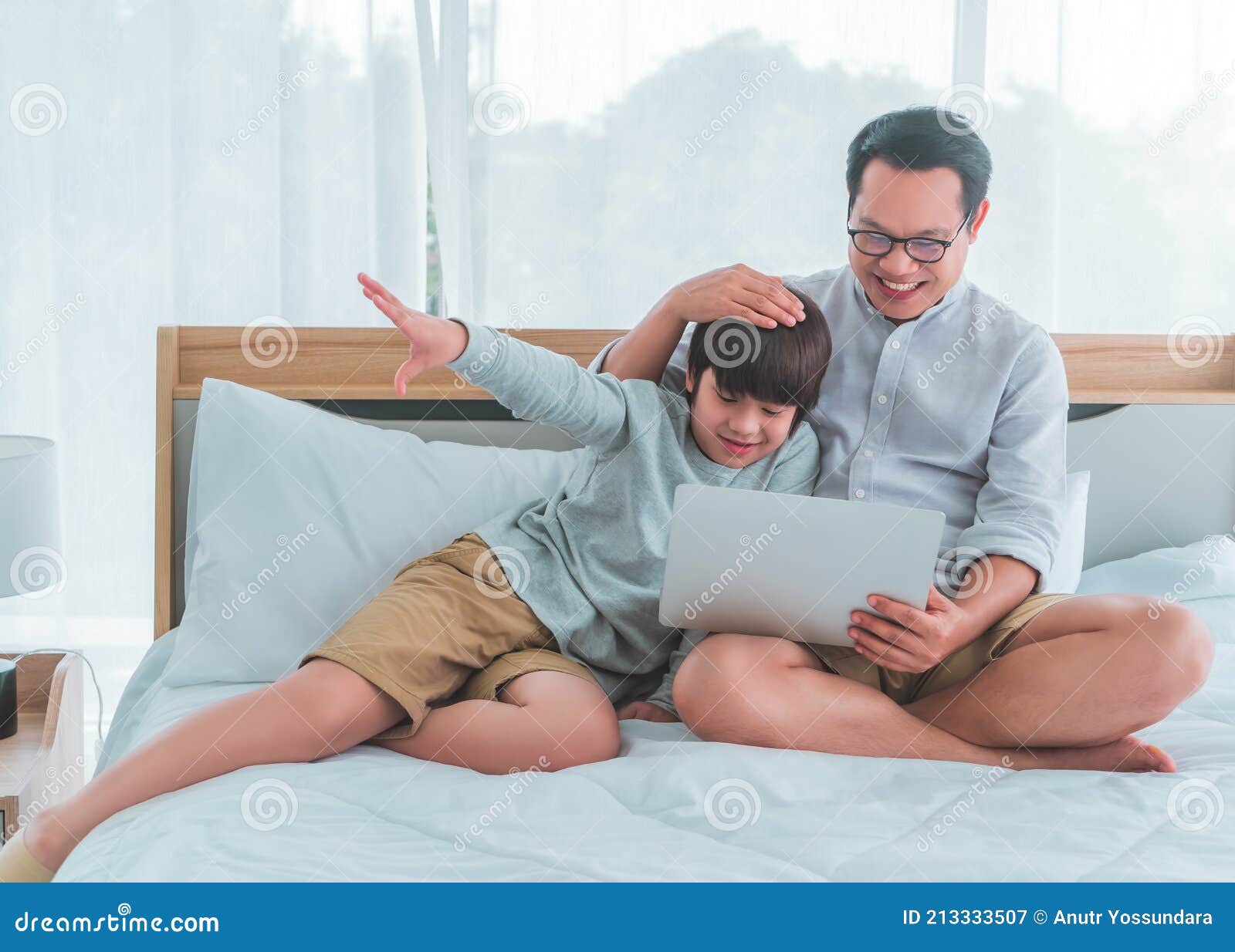 Father and Son Using Laptop Computer on the Bed Together for Technology ...