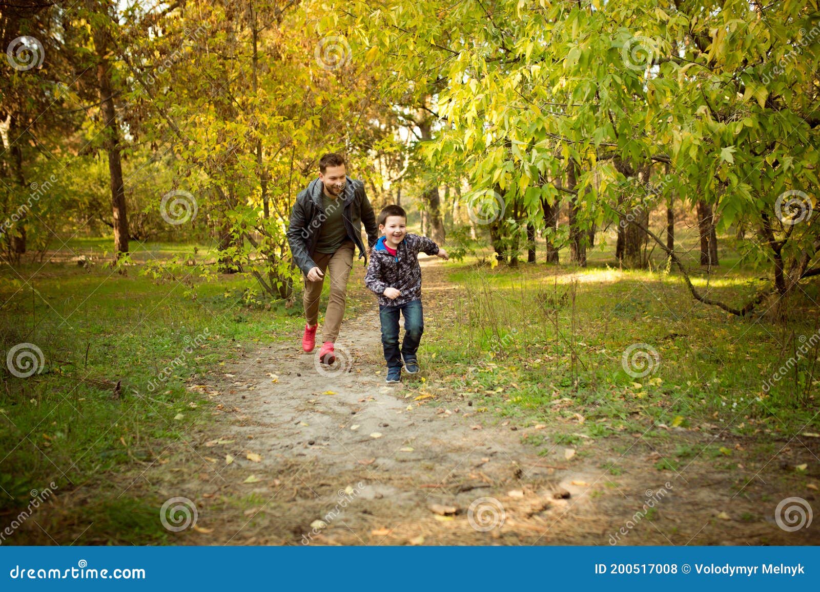 Father And Son Walking And Having Fun In Autumn Forest Look Happy And