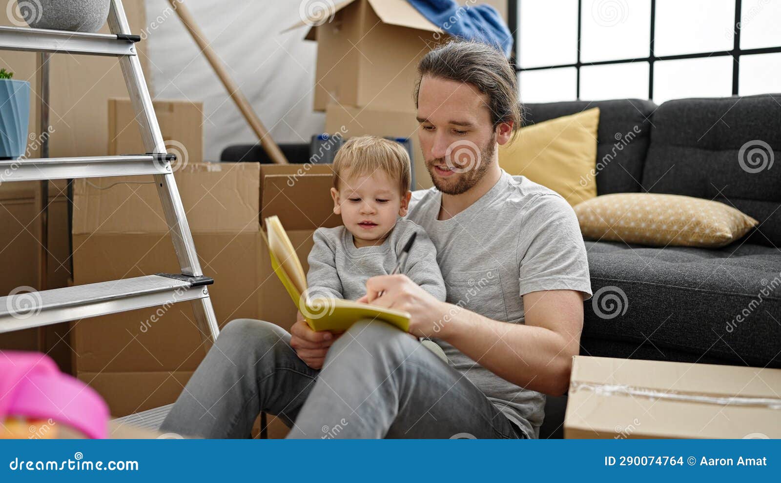 Father and Son Writing on Notebook Sitting on Floor at New Home Stock ...