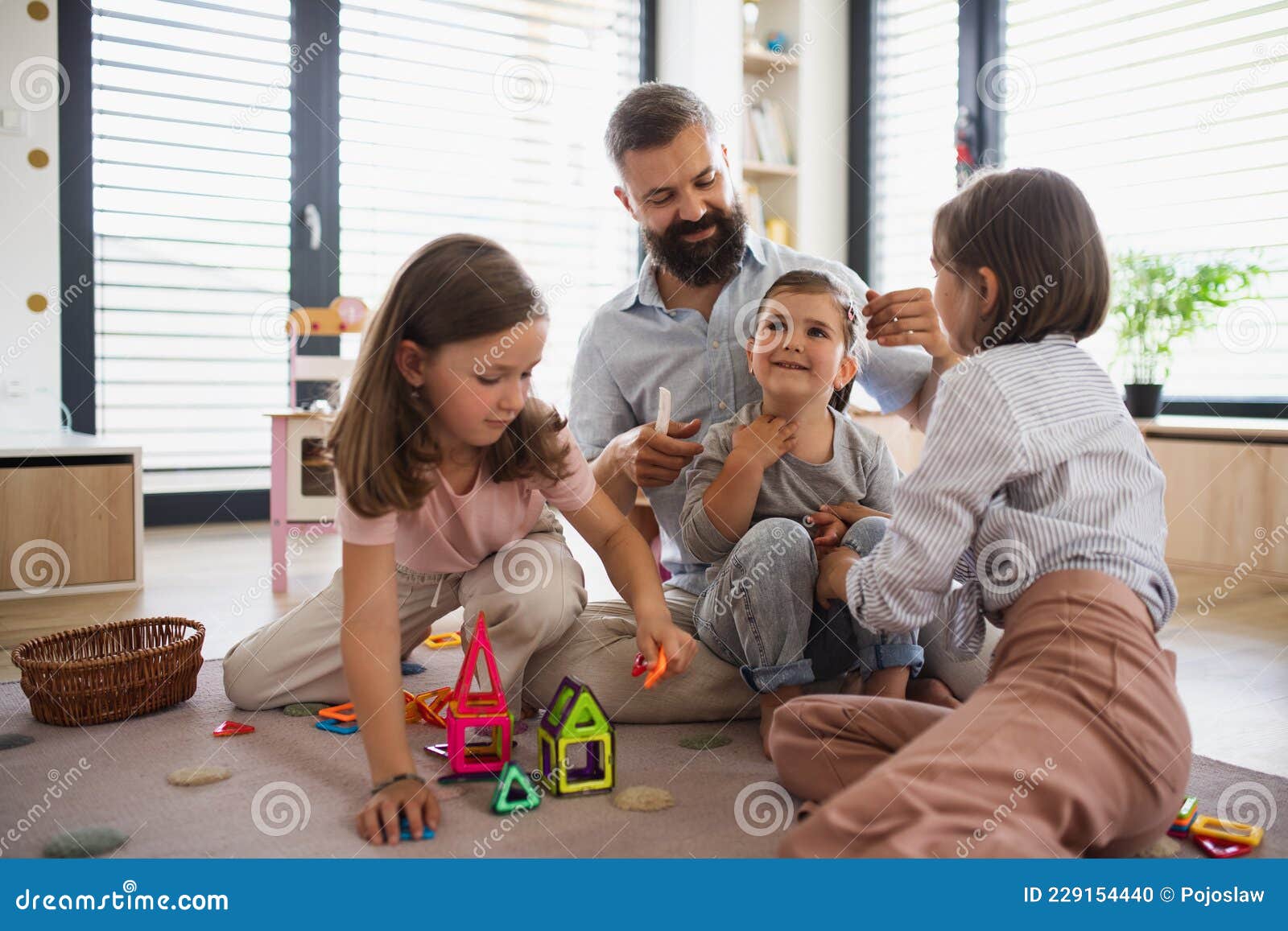 Father With Three Daughters Indoors At Home Playing On Floor Stock