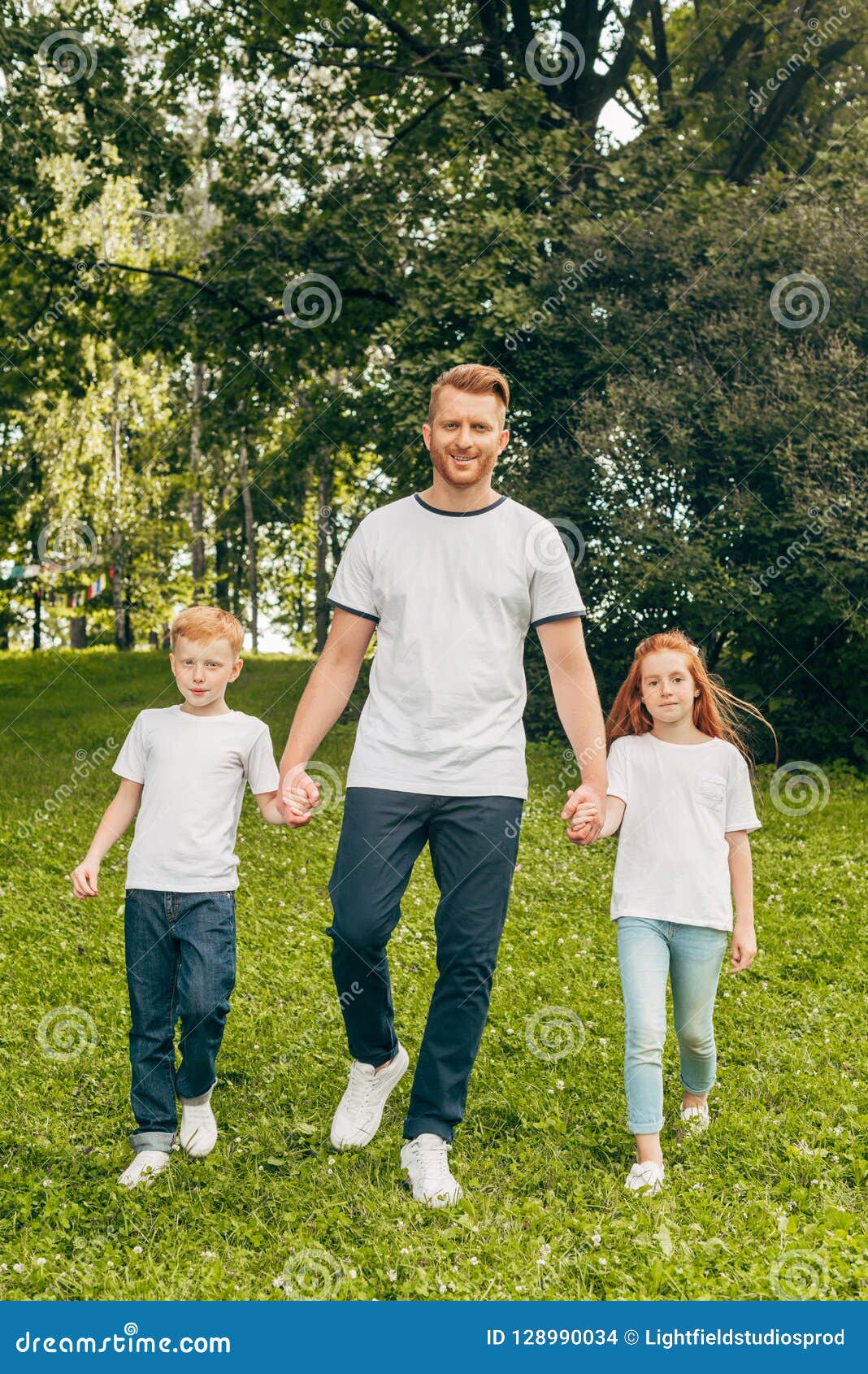 Father with Two Adorable Kids Holding Hands and Smiling at Camera while ... Father with Two Adorable Kids Holding Hands and Smiling at Camera while ...