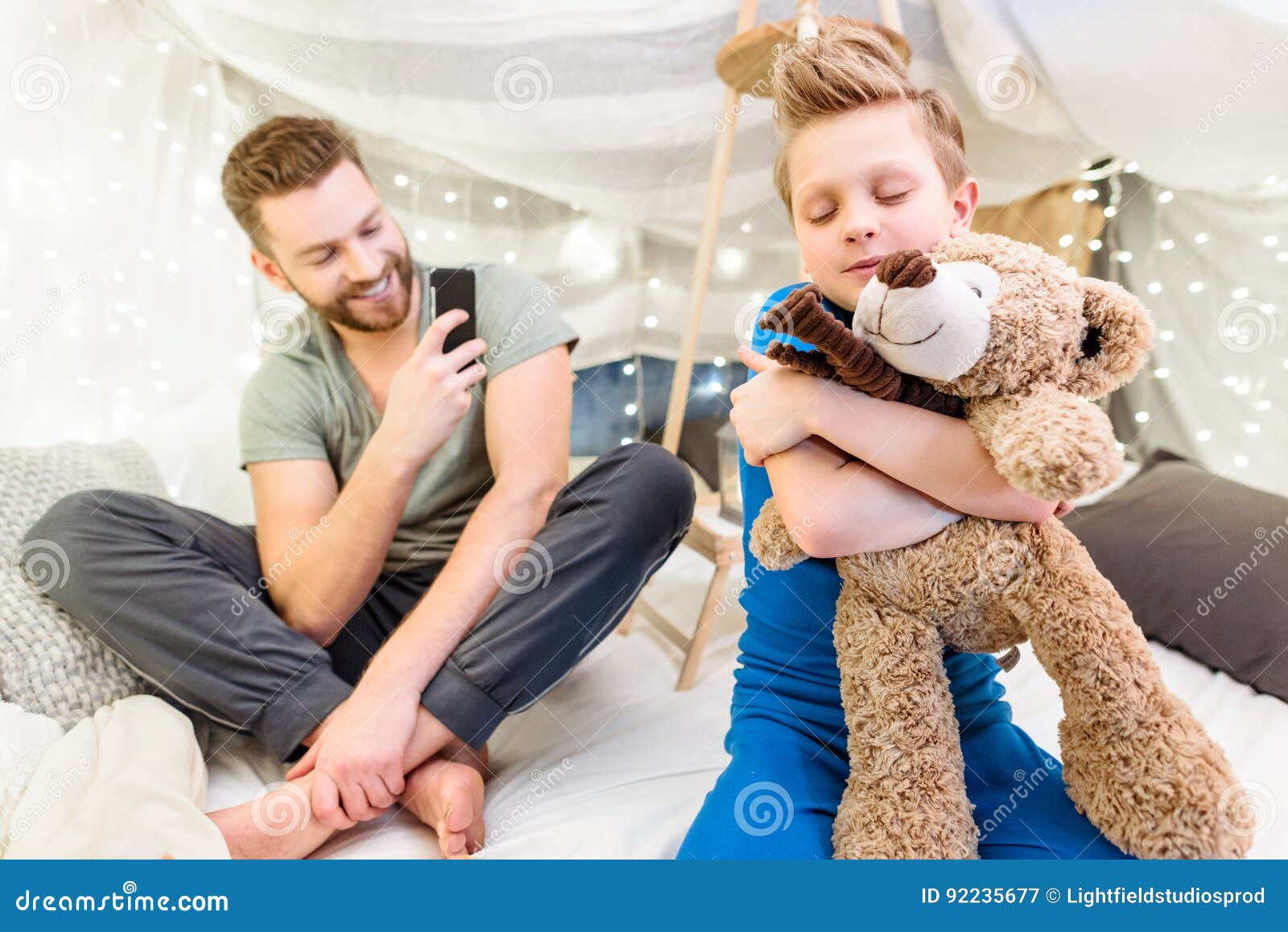 Father Using Smartphone while Little Son Hugging with Teddy Bear Stock ...