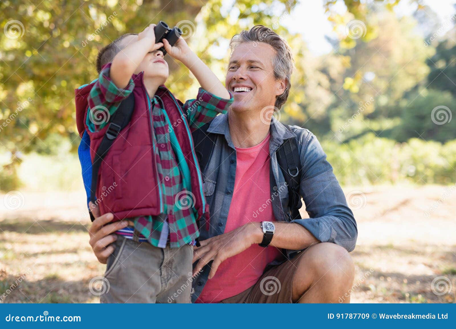 Father Watching at Boy Looking through Binoculars Stock Image - Image ...