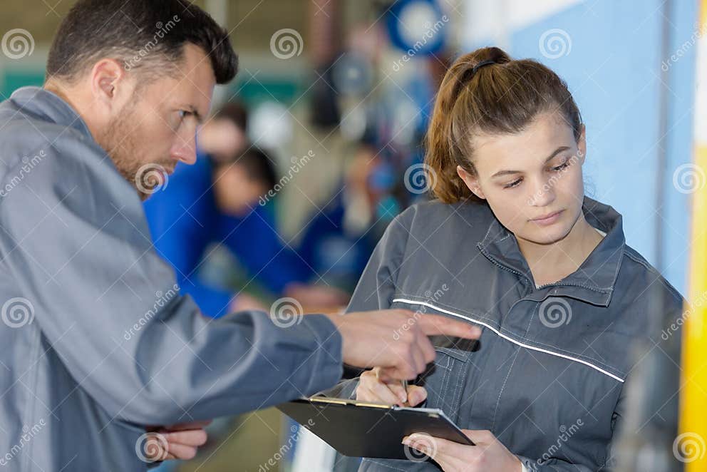 Female Apprentice in Overalls Holding Clipboard Stock Image - Image of ...