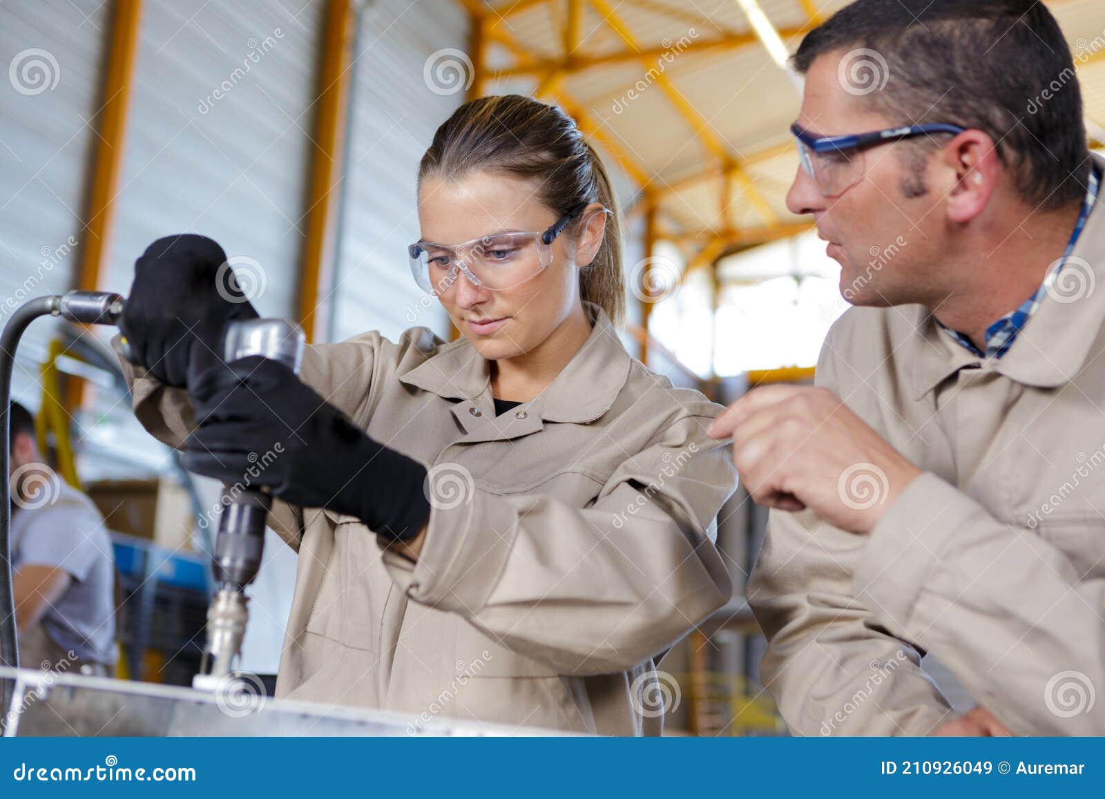 Female Apprentice Using Drill Under Supervision Stock Image - Image of ...