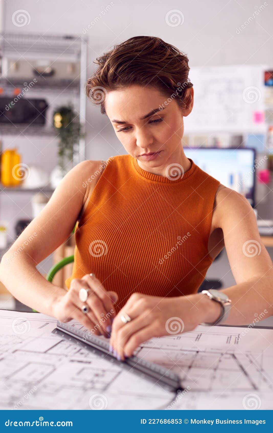 Female Architect at Desk in Office Measuring Plan or Blueprint with ...