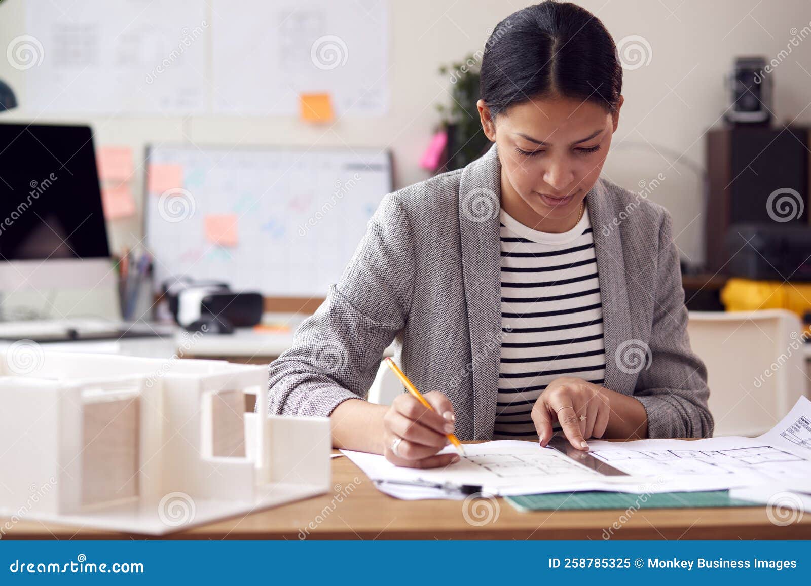 Female Architect Working in Office with Model on Desk Studying Plans ...