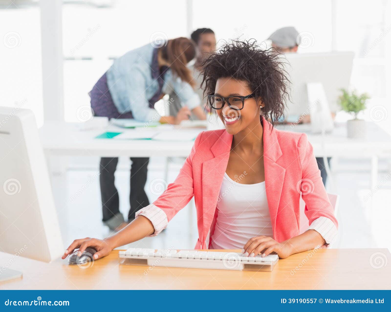 Female Artist Using Computer with Colleagues in Background at Office ...