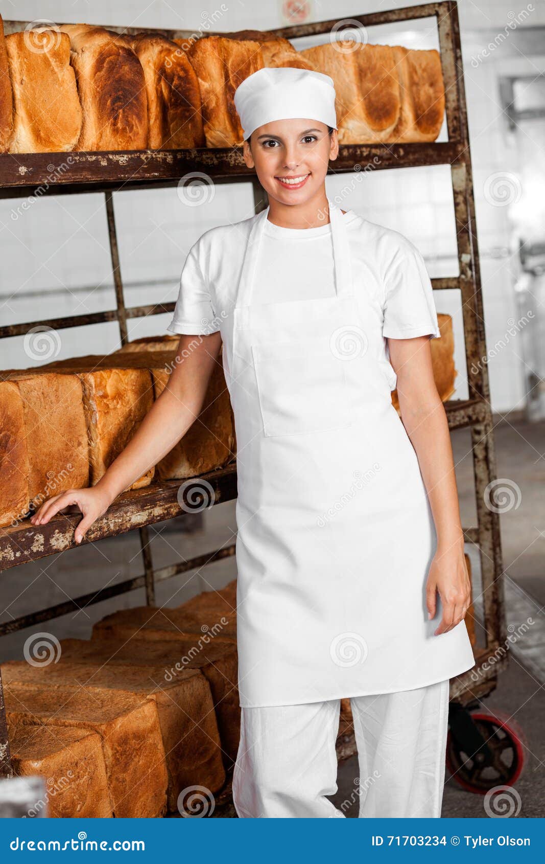 Female Baker Smiling while Standing by Bread Rack Stock Photo - Image ...