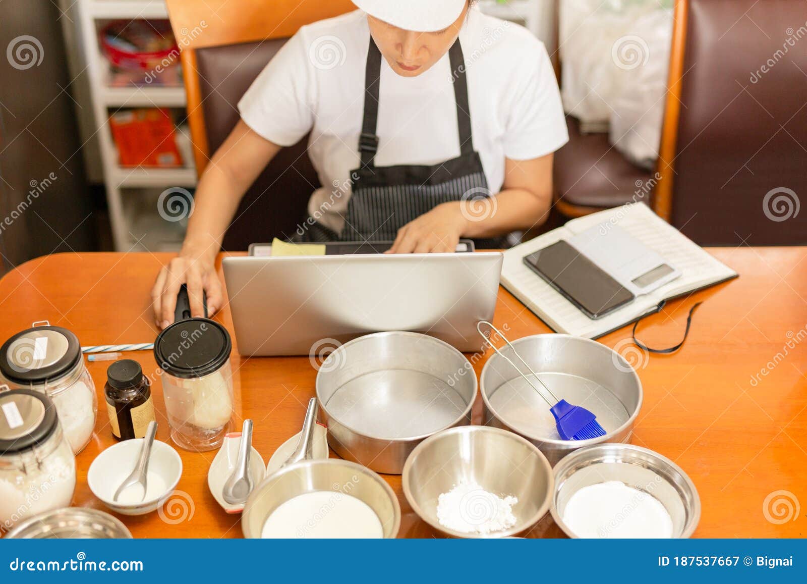 Female Baker Working on Laptop with Bakery Ingredient on Table. Stock ...
