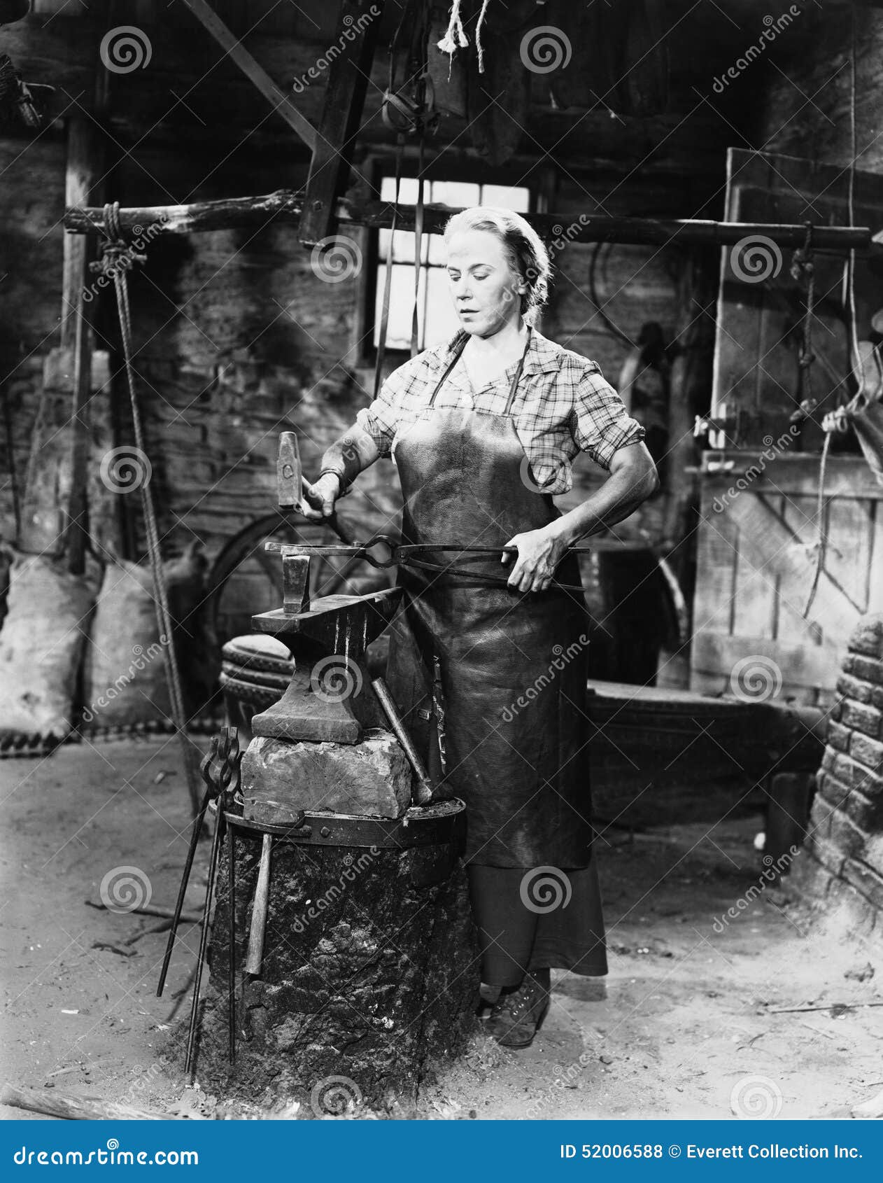 Female Blacksmith Working On Design In Forge Whilst Using Mobile Phone ...