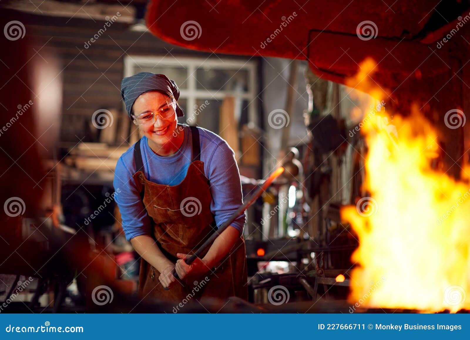 Female Blacksmith Working On Design In Forge Whilst Using Mobile Phone ...