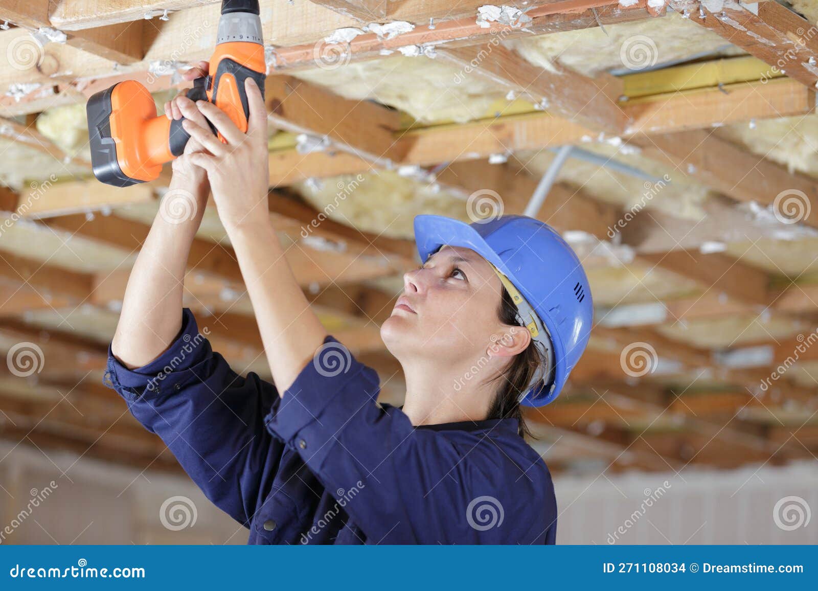 Female Builder Using Cordless Drill on Ceiling Joists Stock Photo ...