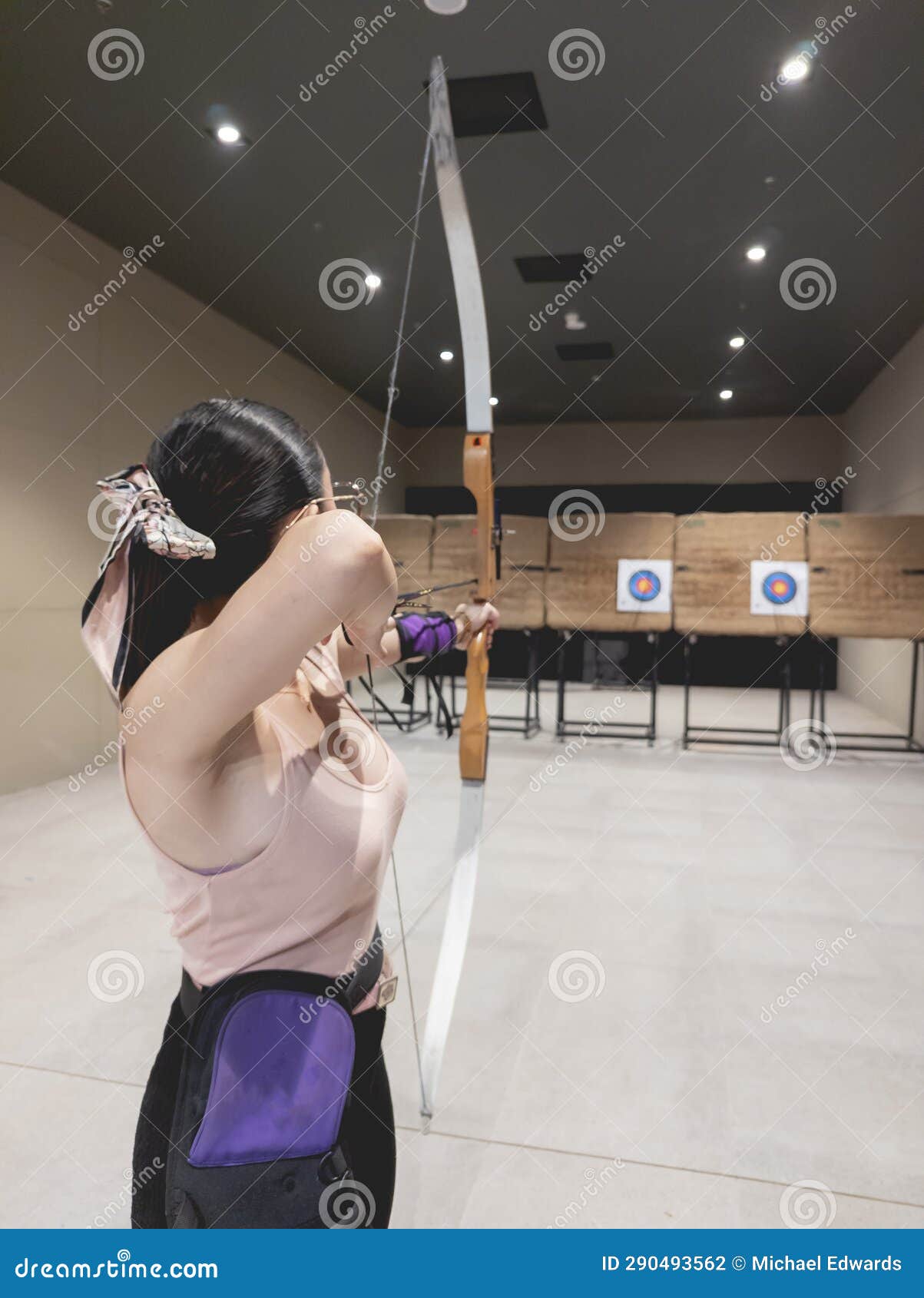 A Female Casual Hobbyist Doing Target Practice at an Indoor Archery ...