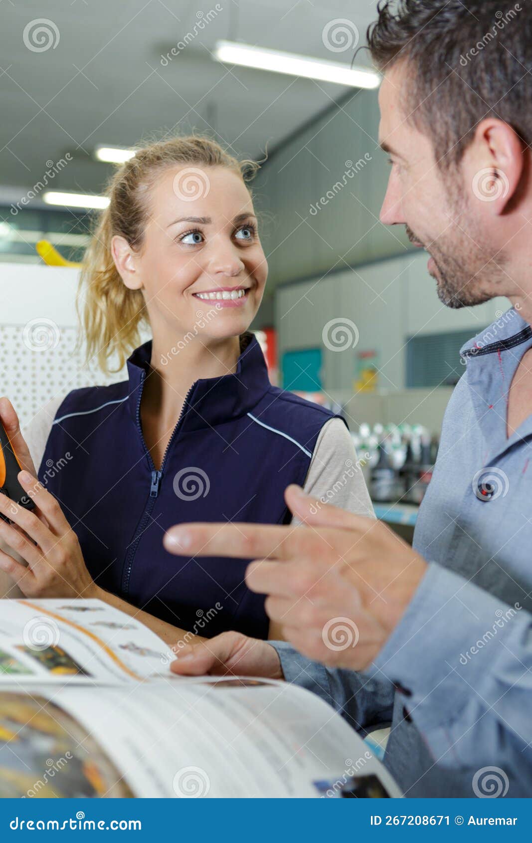 Female Clerk Looking through Catalogue with Male Client Stock Image ...