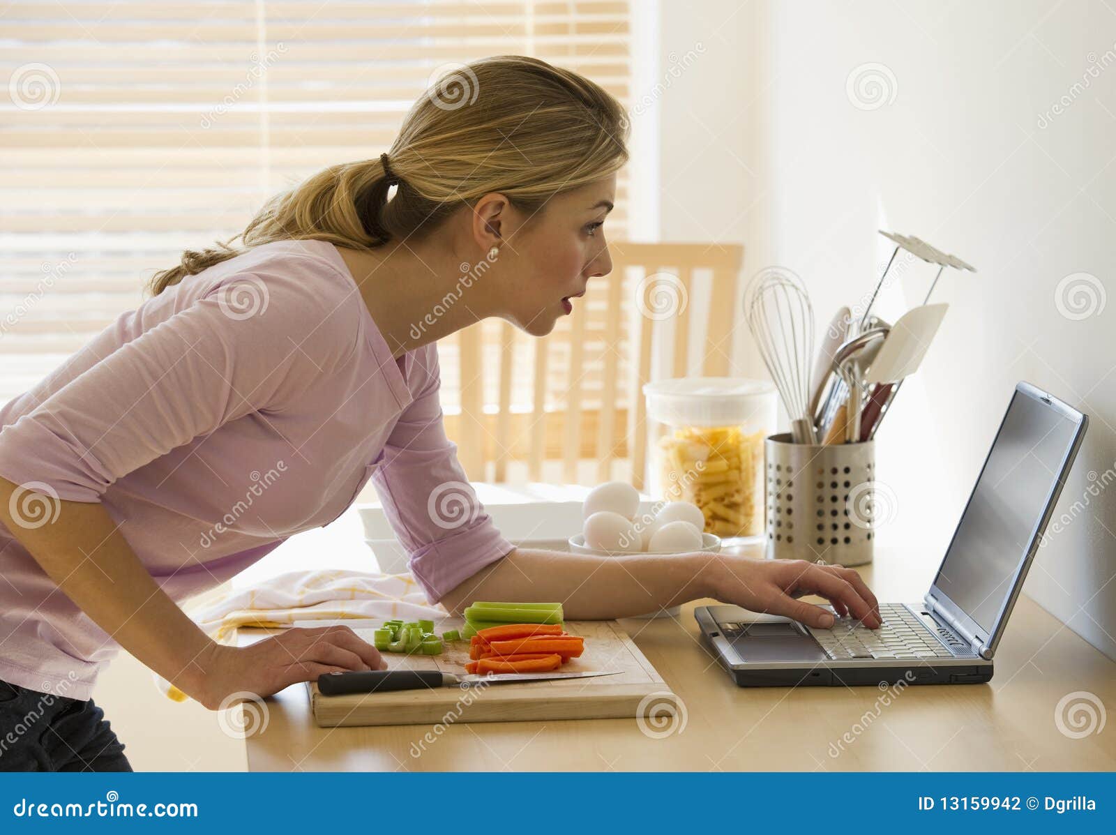 Female Cooking and Looking at Laptop in Kitchen Stock Photo - Image of ...