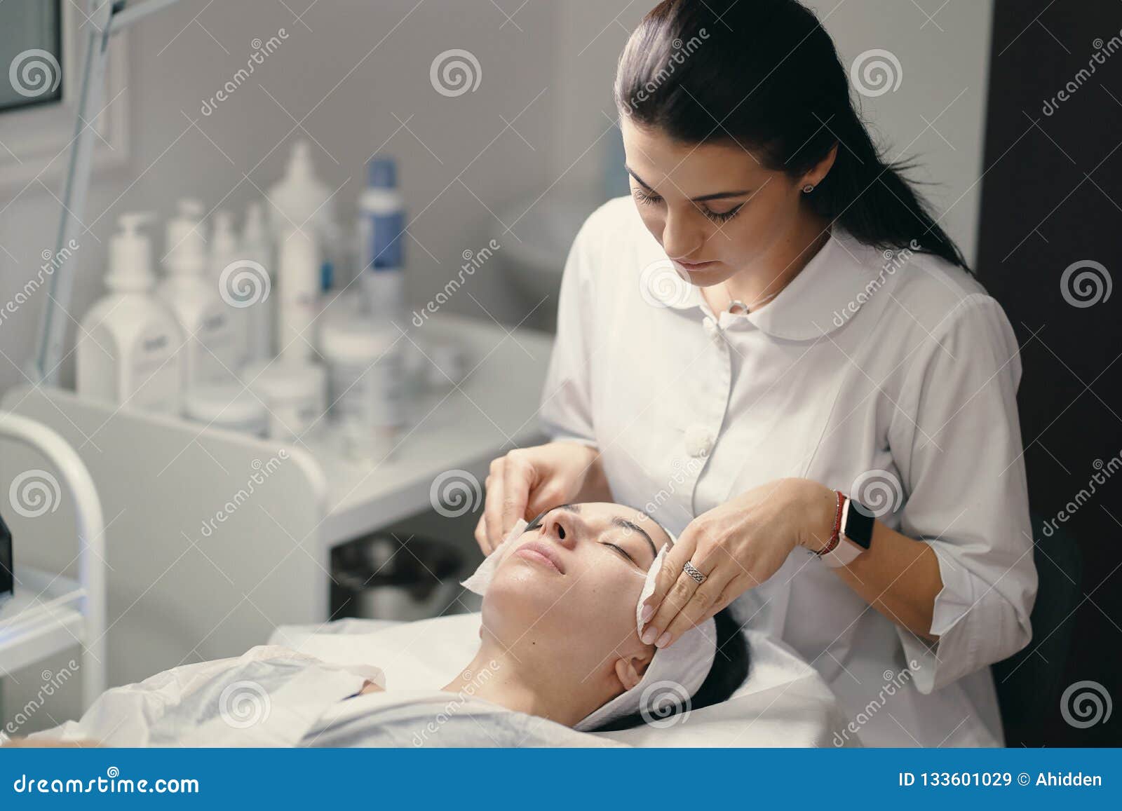 Female Cosmetologist Making Facial Treatment To A Beautiful Woma Stock