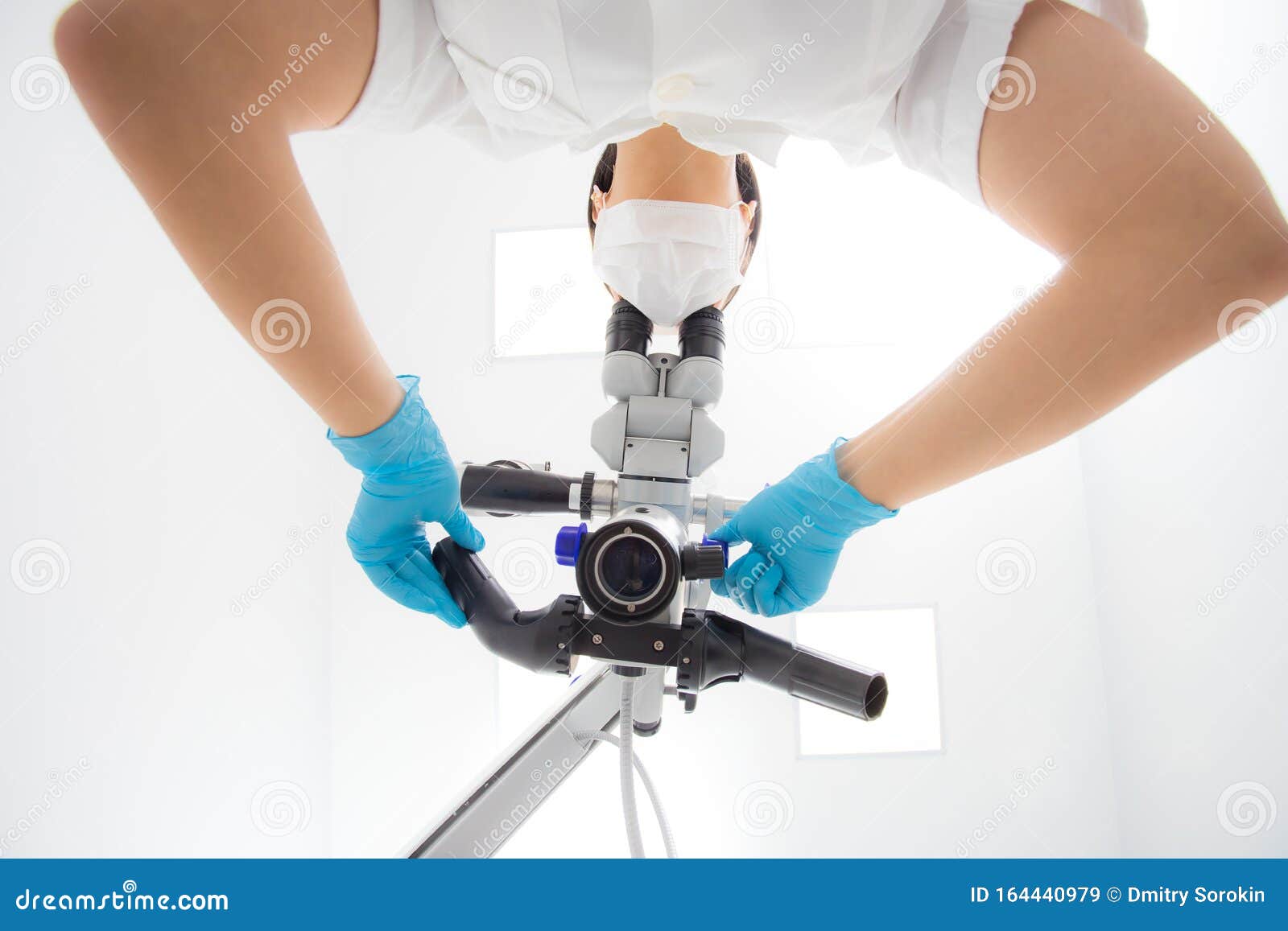 A Female Dentist is Looking into a Dental Microscope. Bottom View Stock ...
