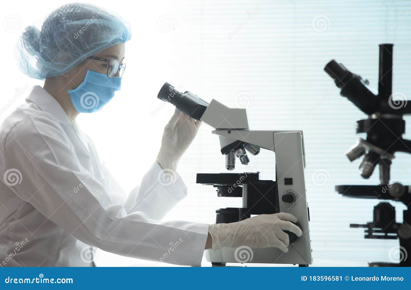 Female Doctor with Cap and Face Mask Using Light Microscope Stock Image ...