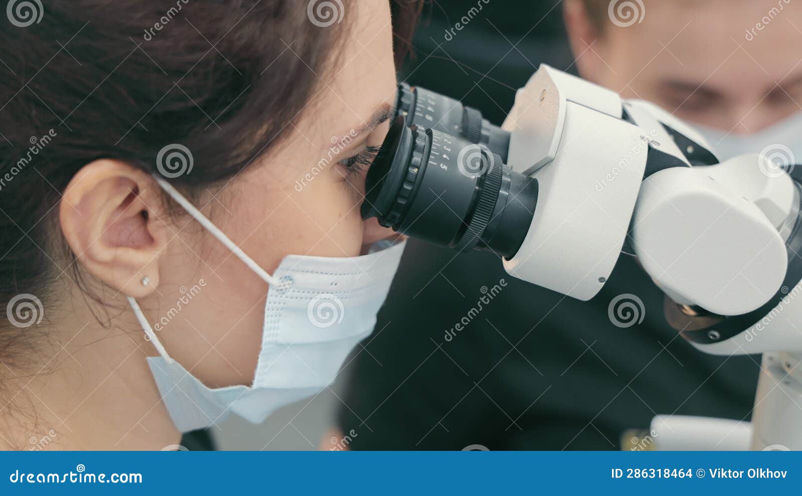 A Female Doctor Looks in a Microscope Close-up. Side View of Female ...