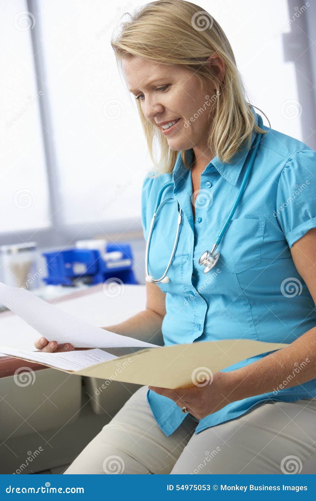 Female Doctor in Surgery Reading Patient Notes Stock Image - Image of ...