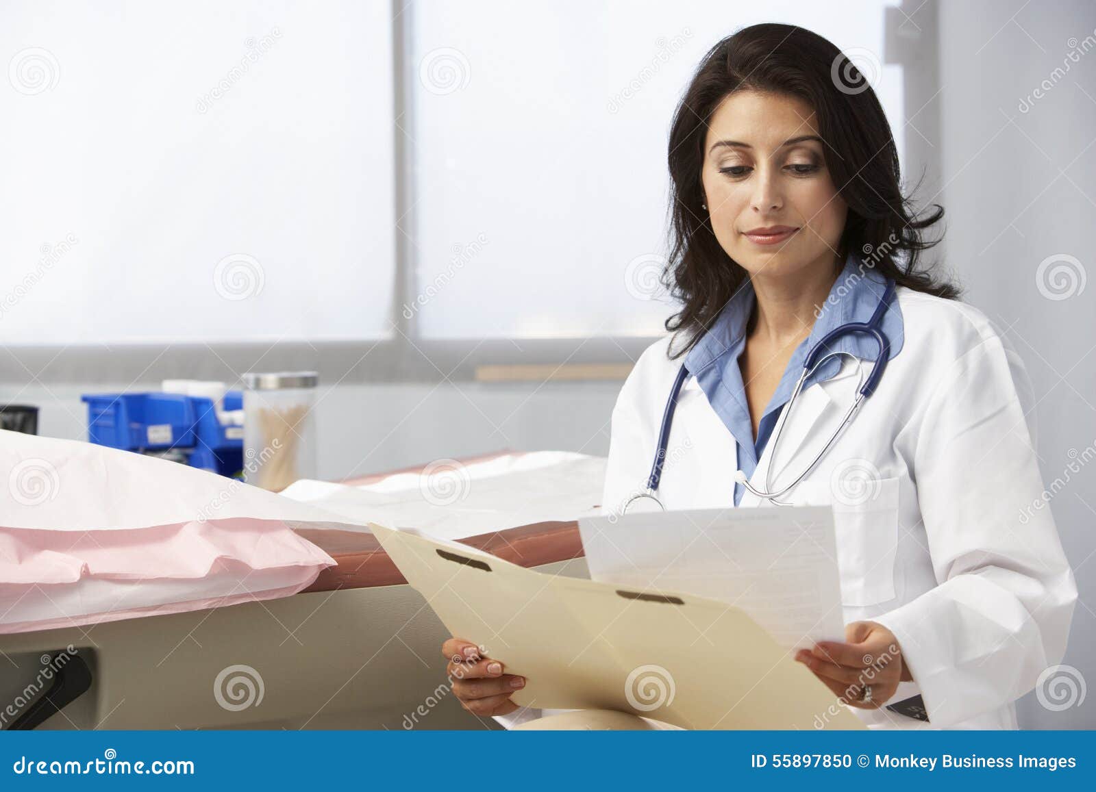 Female Doctor in Surgery Reading Patient Notes Stock Photo - Image of ...