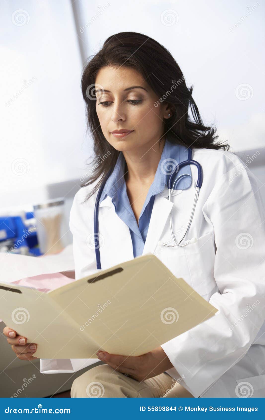 Female Doctor in Surgery Reading Patient Notes Stock Photo - Image of ...
