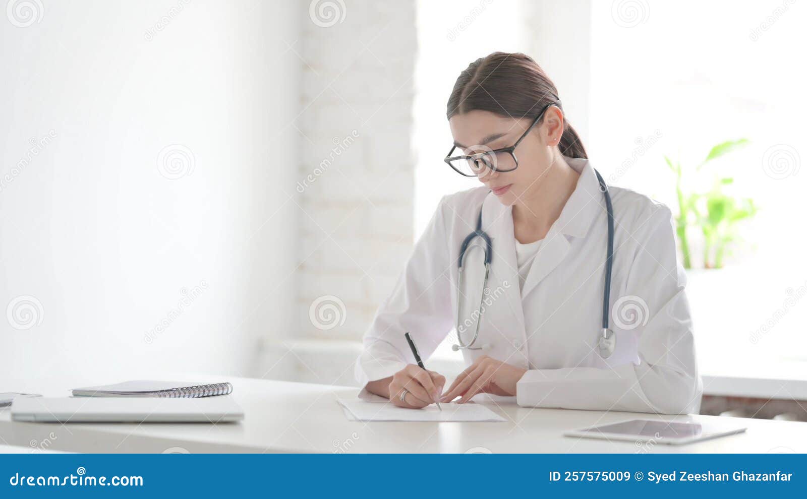 Female Doctor Writing on Paper in Office Stock Image - Image of serious ...