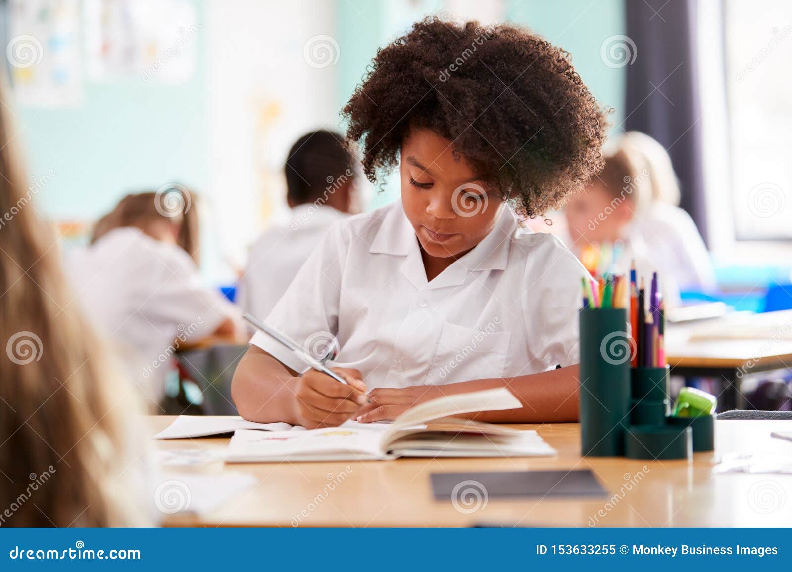 Female Elementary School Pupil Wearing Uniform Working at Desk Stock ...