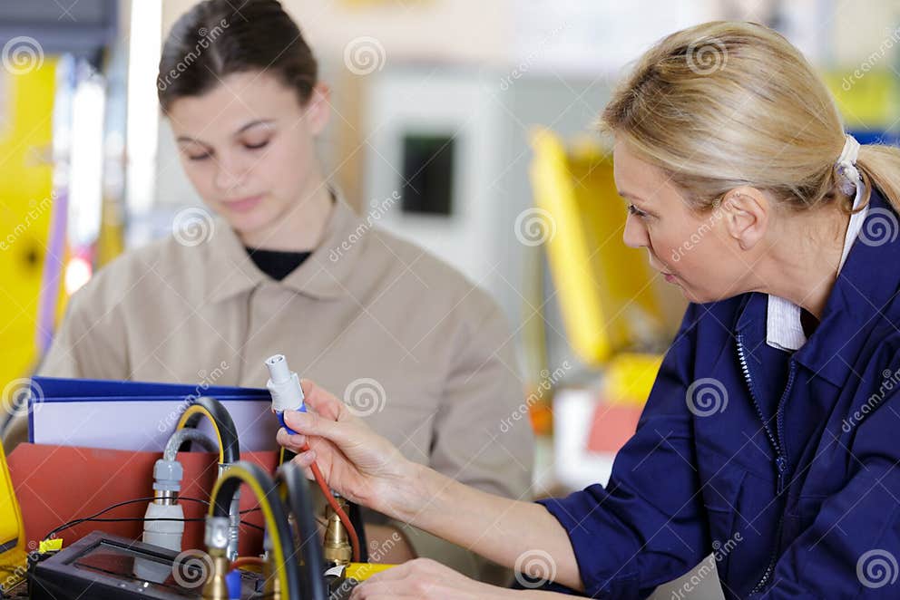 Female Engineer Connecting Hoses with Apprentice Stock Photo - Image of ...