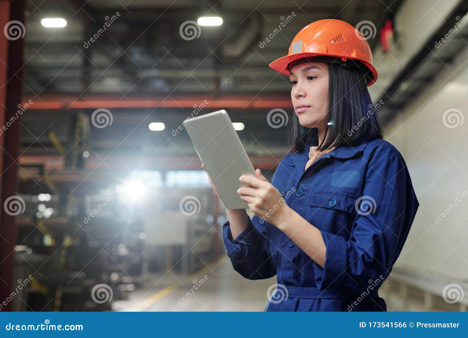 Female Engineer in Hardhat and Blue Uniform Working with Technical Data ...