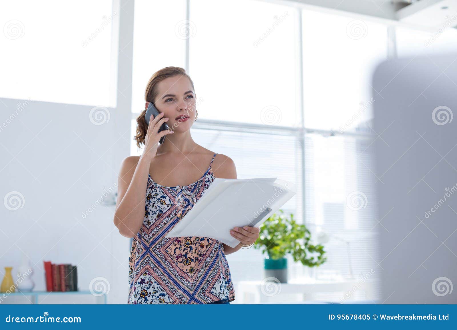 Female Executive Talking on Mobile Phone while Holding Document Stock ...