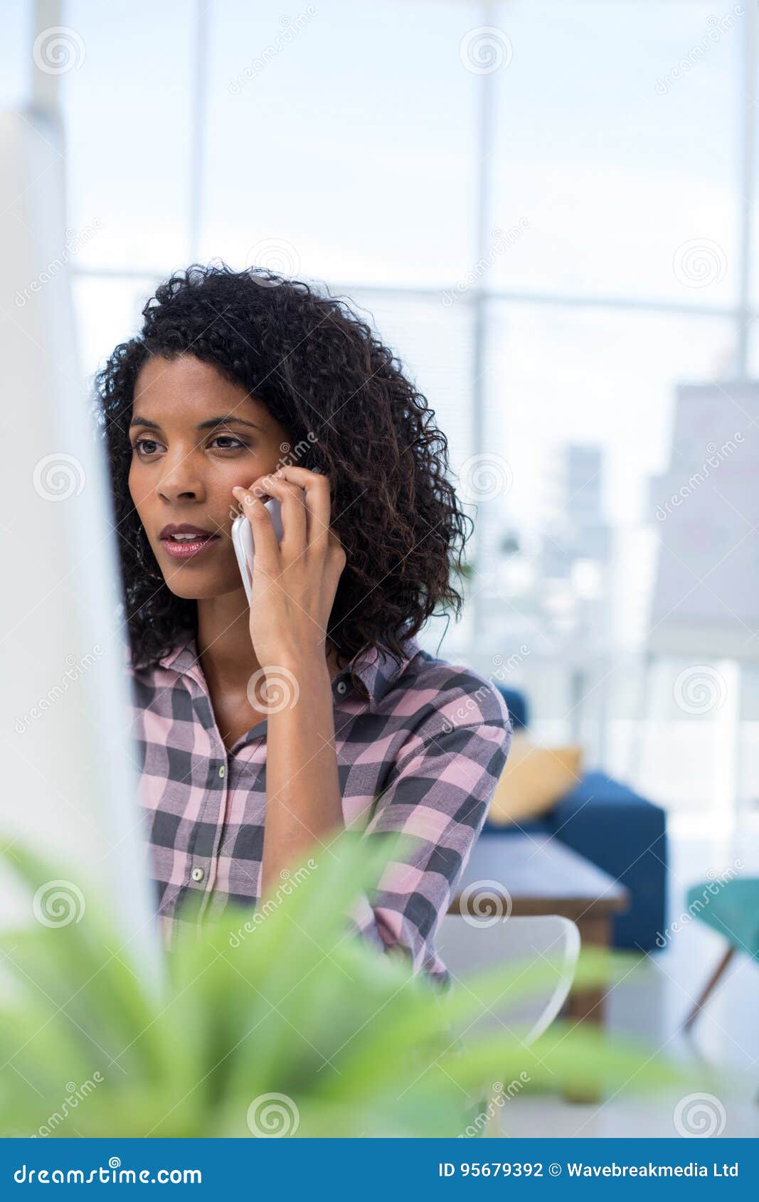 Female Executive Talking on Mobile Phone while Working on Computer at ...