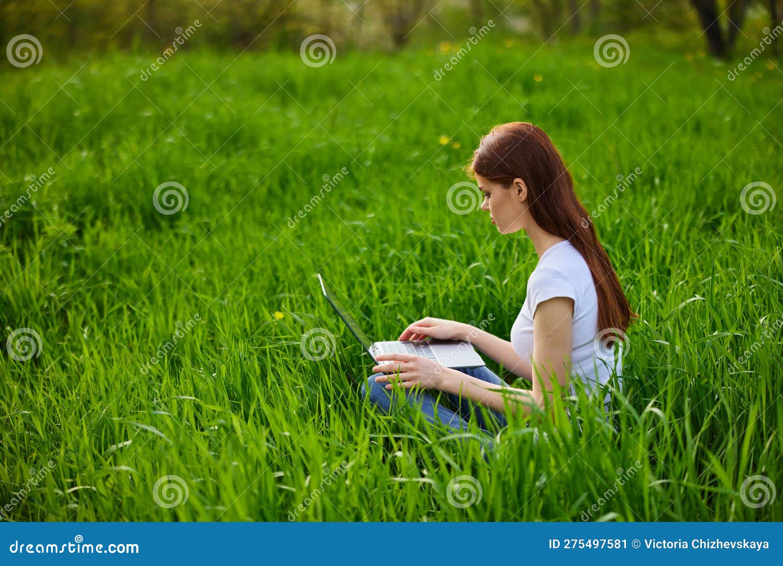 Female Freelancer Working In Nature Sits In The Grass In Nature With A